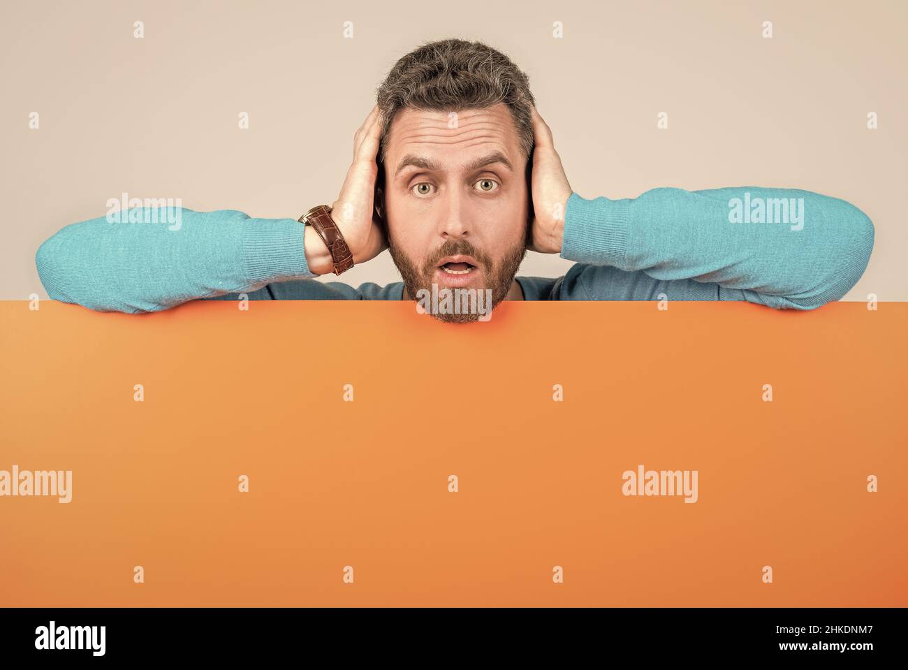 shocked mature man behind blank orange paper banner with copy space for ...