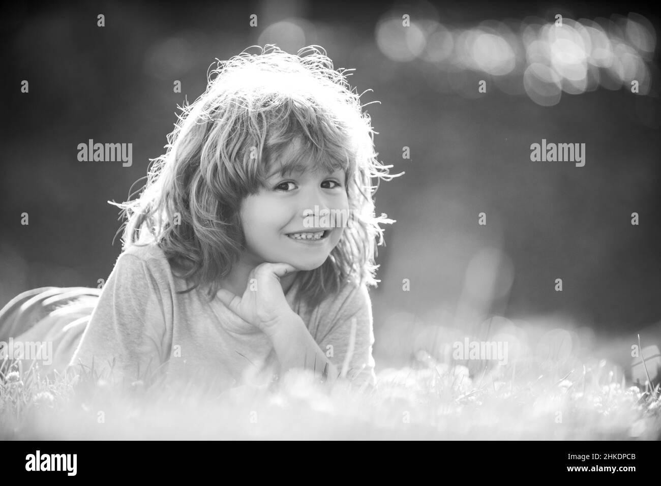 Portrait of a happy laughing child laying on grass in summer nature ...