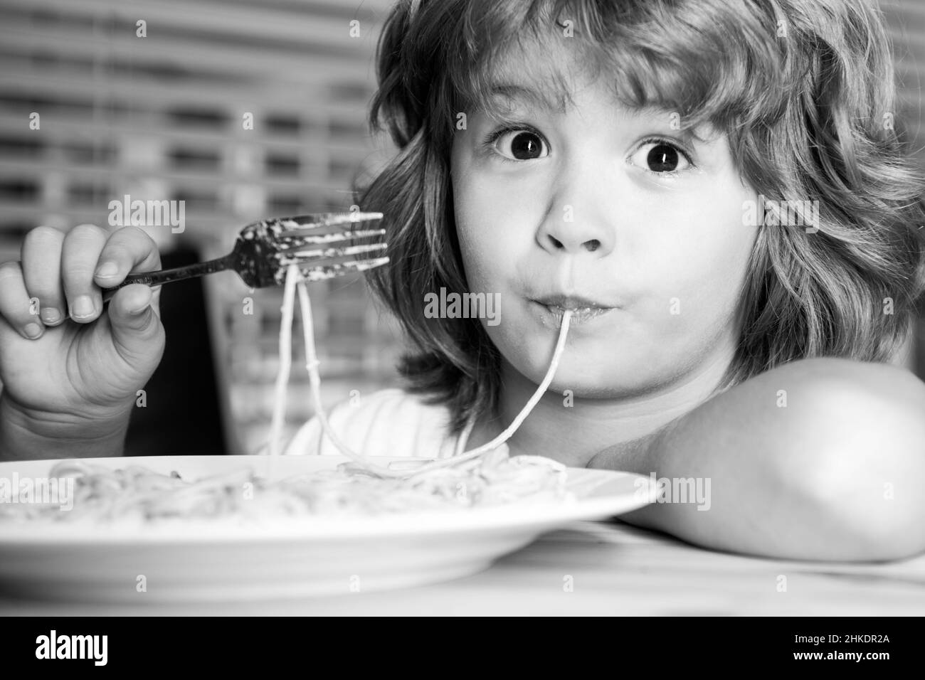 Funny child eating pasta, spaghetti, face close up. Kids head portrait ...