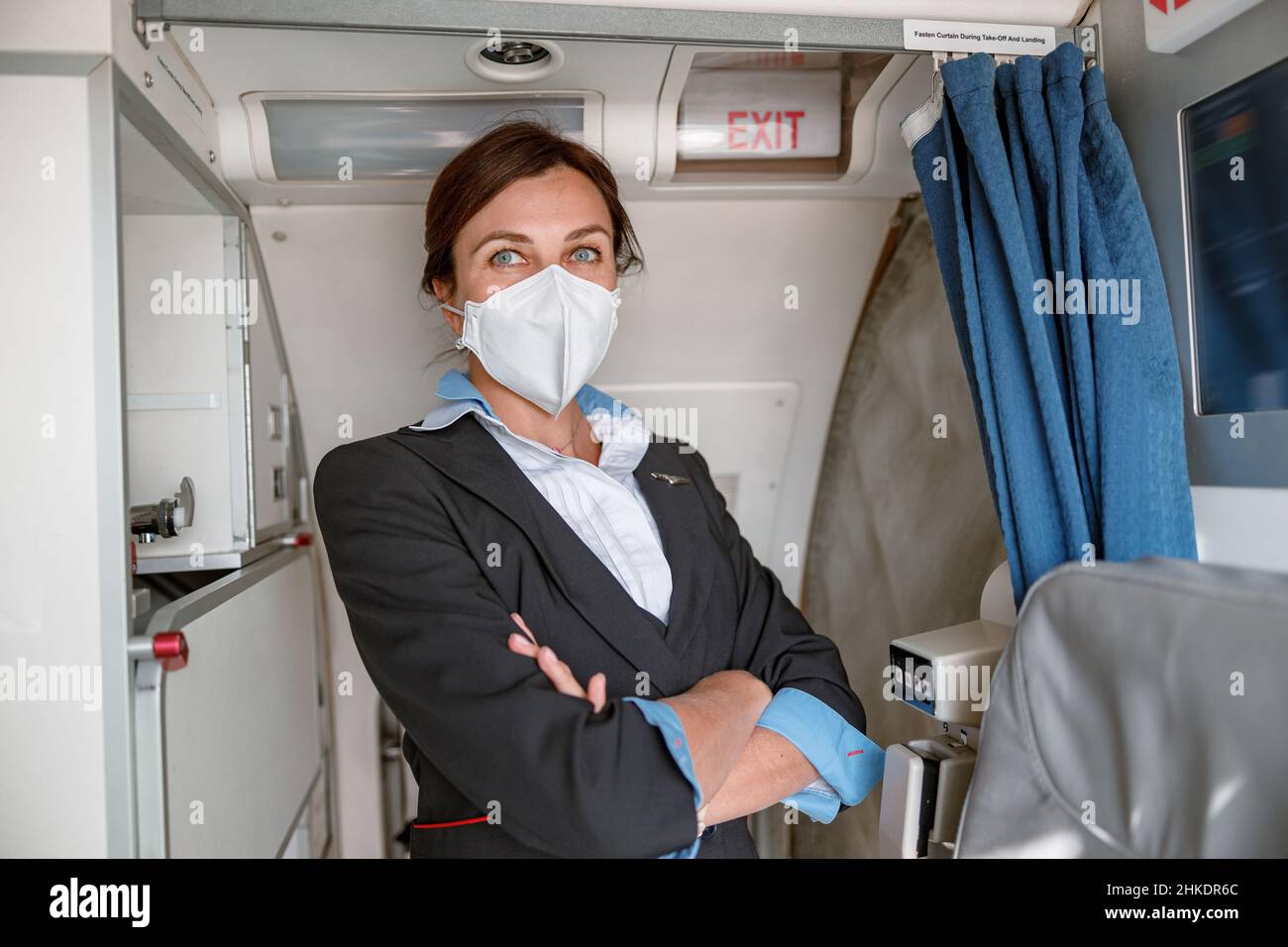 Woman flight attendant in medical mask standing in airplane Stock Photo ...
