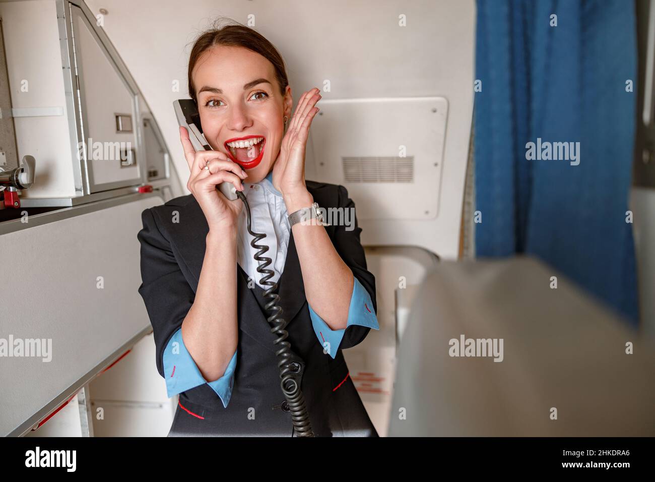 Joyful female flight attendant talking on telephone in airplane Stock ...