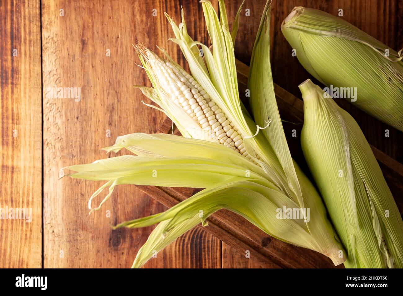 Top view image of raw white corn on the cob on wooden rustic surface ...