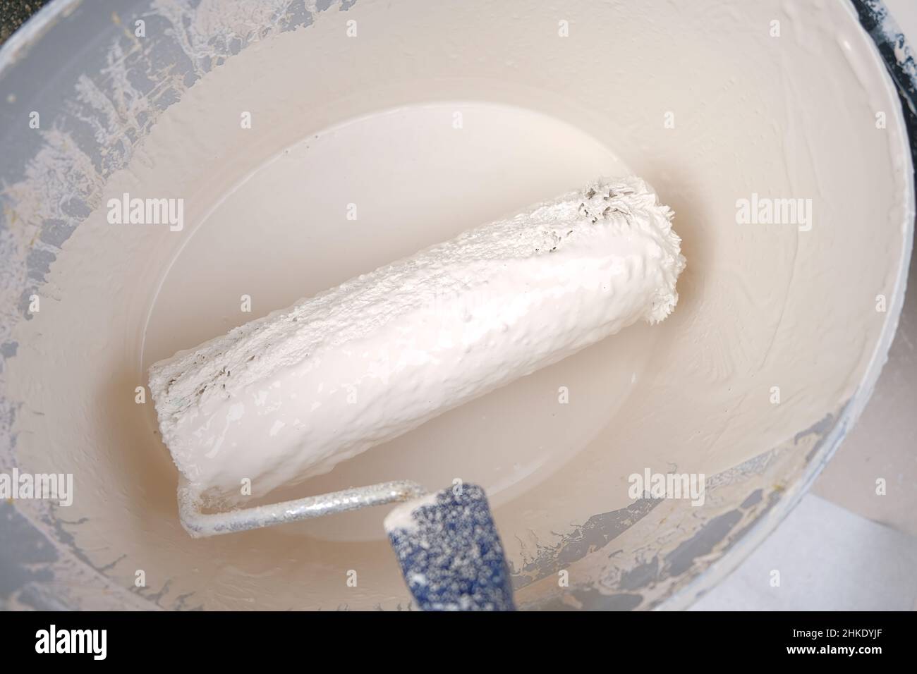 Roller and paint. Construction roller in a bucket with beige paint ...