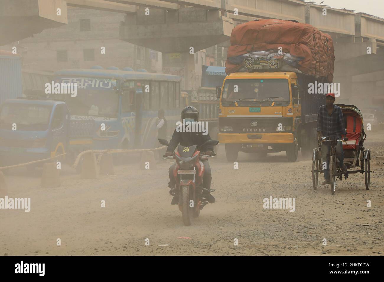 A motorcycle driver seen driving on a dusty air heavily polluted road ...