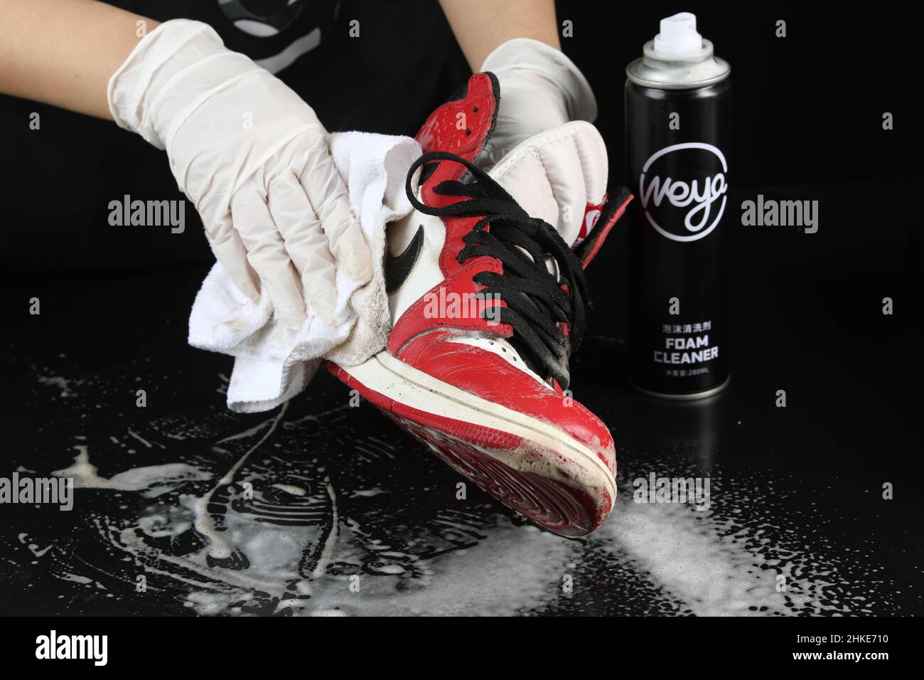 Person washing the sneakers with sneakers foam and a towel indoors ...