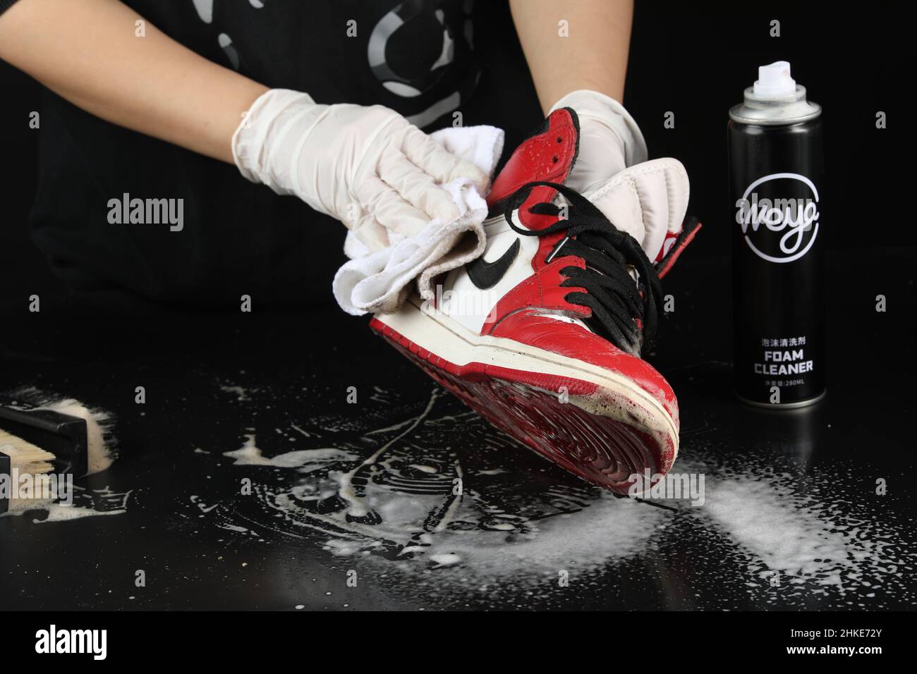 Person washing the sneakers with sneakers foam and a towel indoors ...