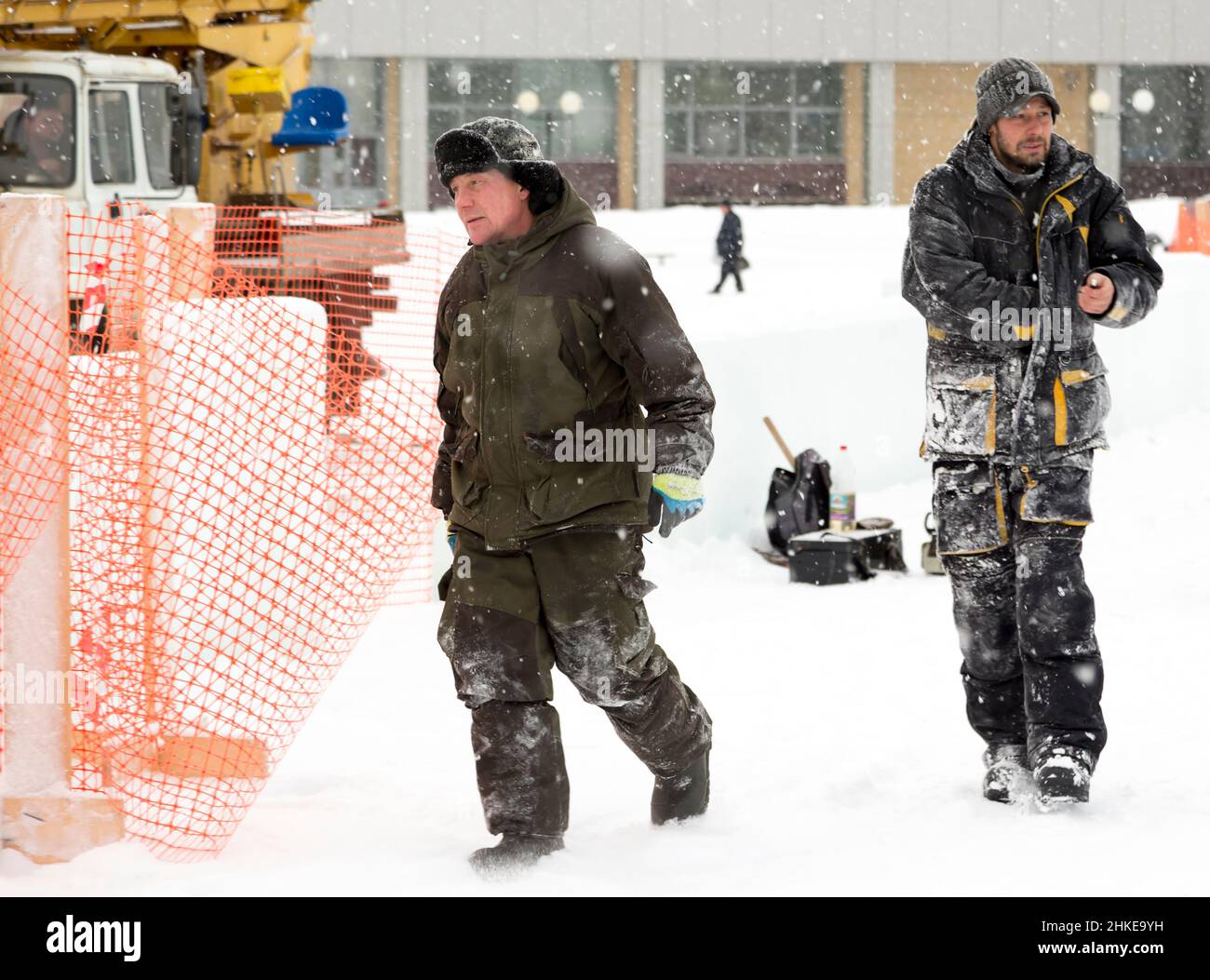 Two assemblers walk along the construction site of the ice town Stock ...
