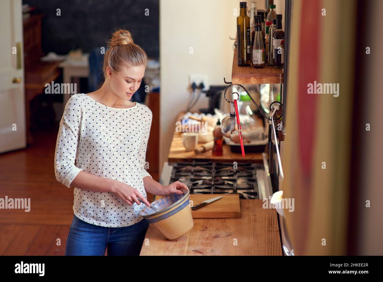 Mixing it all up. Shot of a beautiful young woman preparing food in her ...