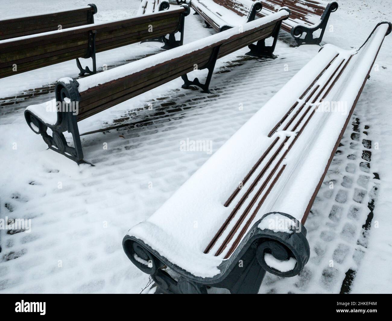benches in a park covered with fresh first snow on frosty snowy day ...