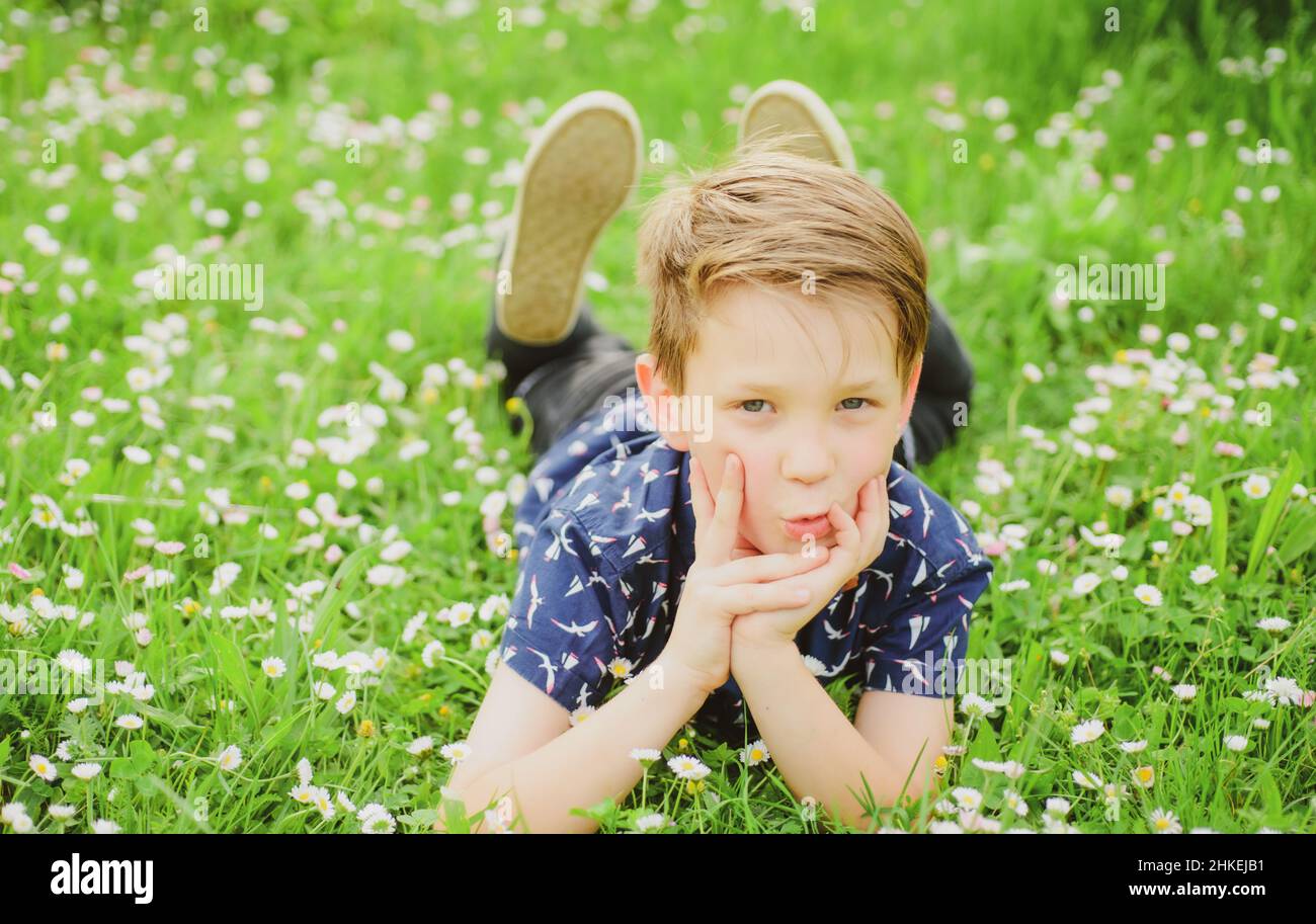 Spring boy resting on grass. Cute kid on field flower. Dreaming child ...