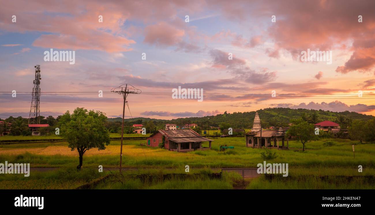 Traditional Indian village house and temple surrounded by green grass ...