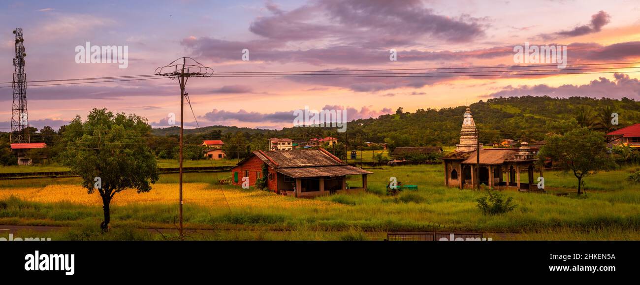 Traditional Indian village house and temple surrounded by green grass ...
