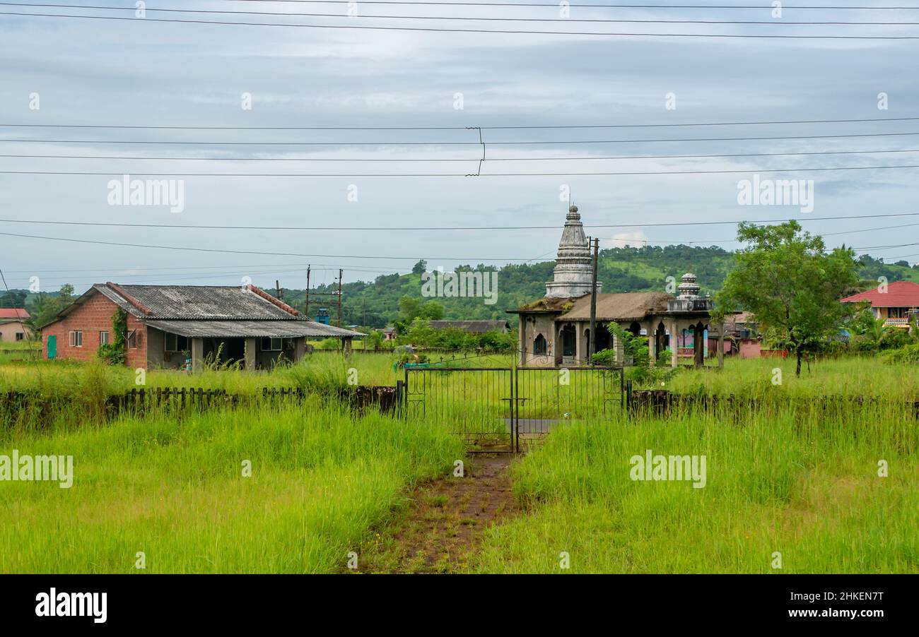 Traditional Indian village house and temple surrounded by green grass ...