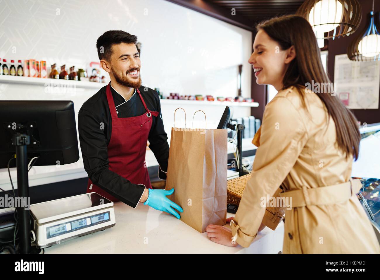 Shop assistant handling shopping bag to female customer in grocery ...