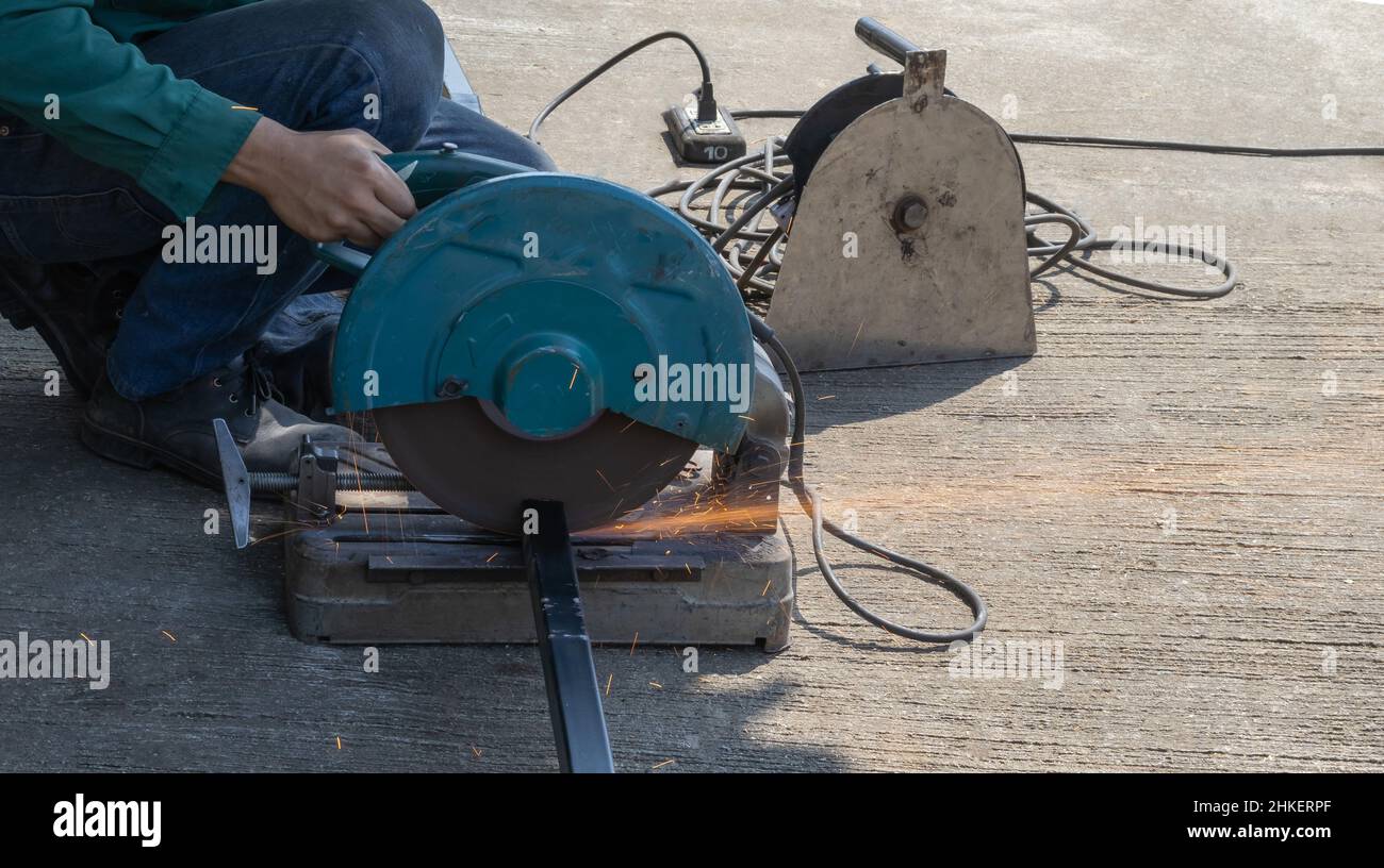 A technician is cutting steel using a cutting machine. Sparks splashed ...