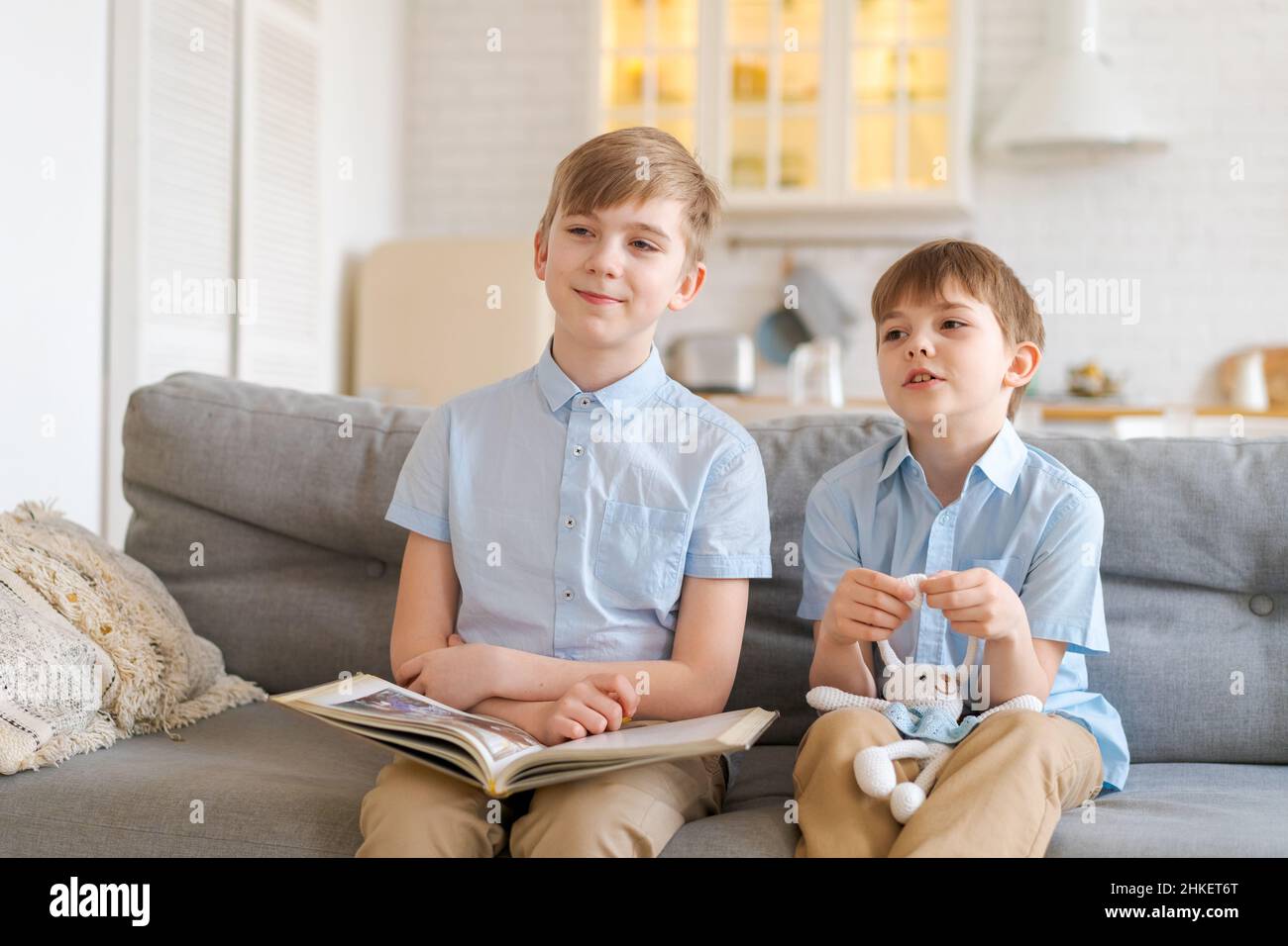 An older brother is reading book to his younger brother sitting on ...