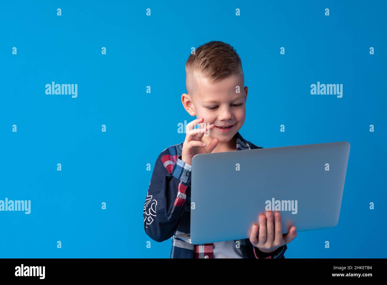 Smart little boy with laptop isolated over blue background Stock Photo ...