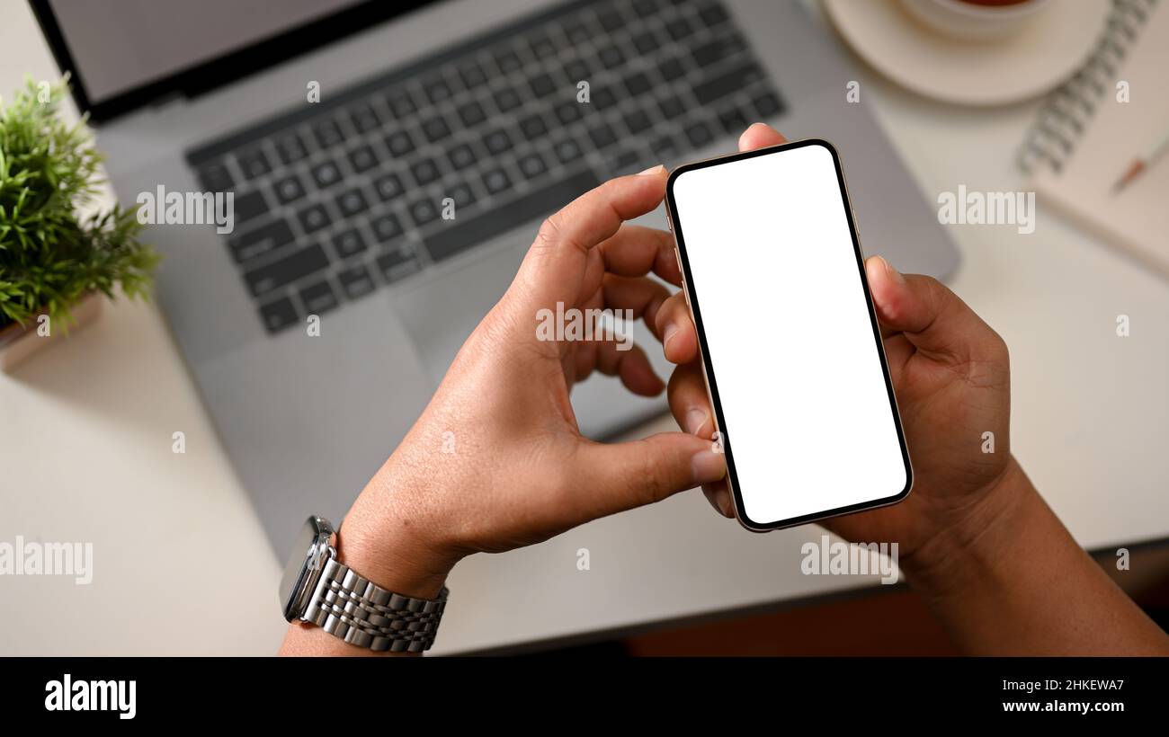 Top view of an adult male hands holding a smartphone white screen ...