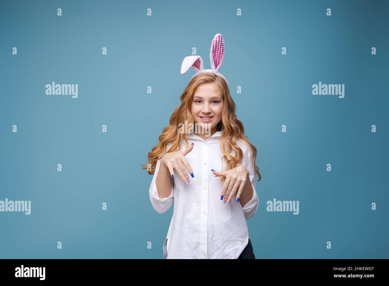 Girl in pink rabbit ears on her head on blue studio background ...