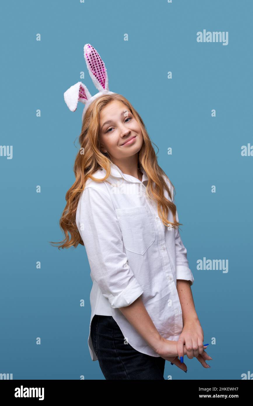 Girl in pink rabbit ears on her head on blue studio background ...