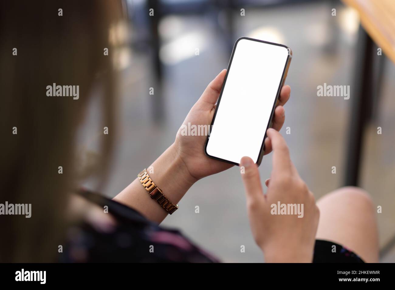 Close-up, back view of a beautiful female holding a smartphone ...