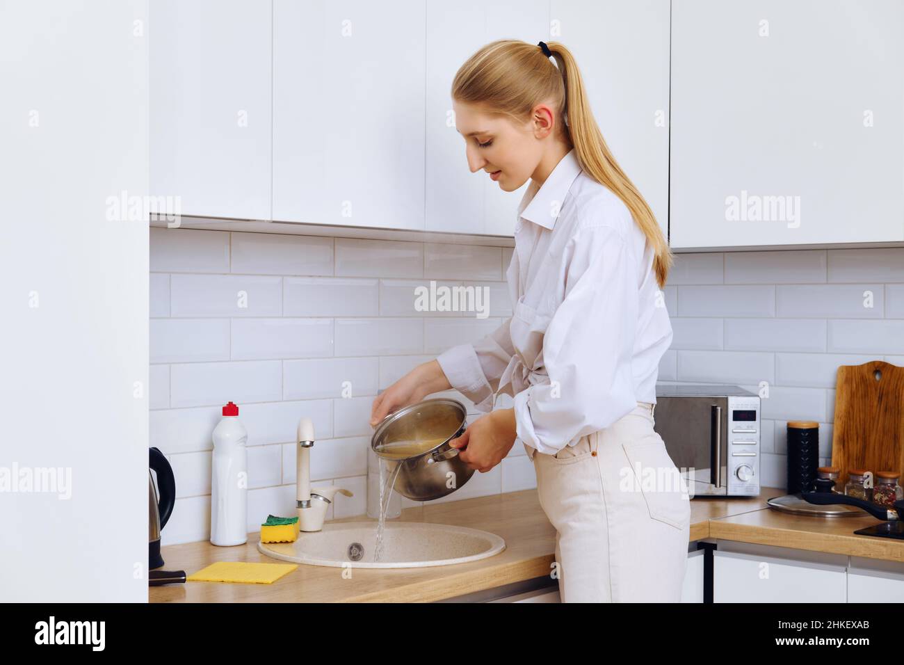 Young woman draining cooked spaghetti from water with stainless ...