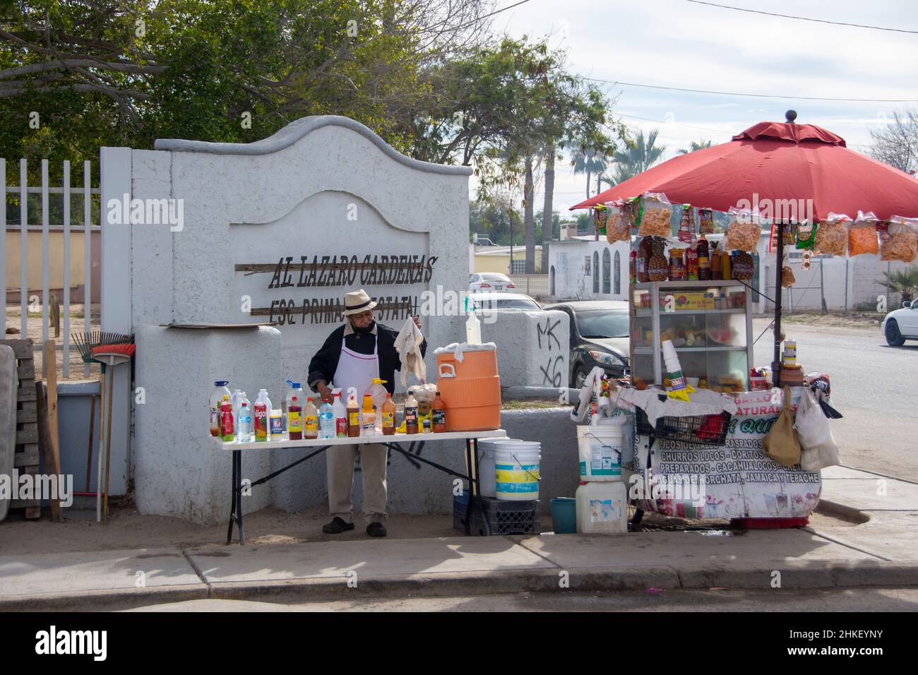 A man selling food from his stand in front of a park in the city of ...