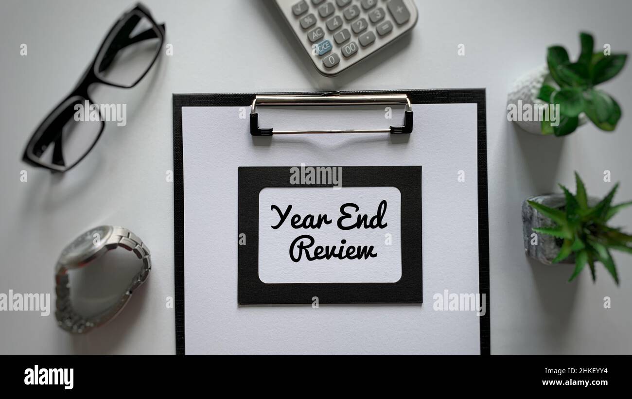 Year end review text on notepad with white paper, glasses, calculator ...