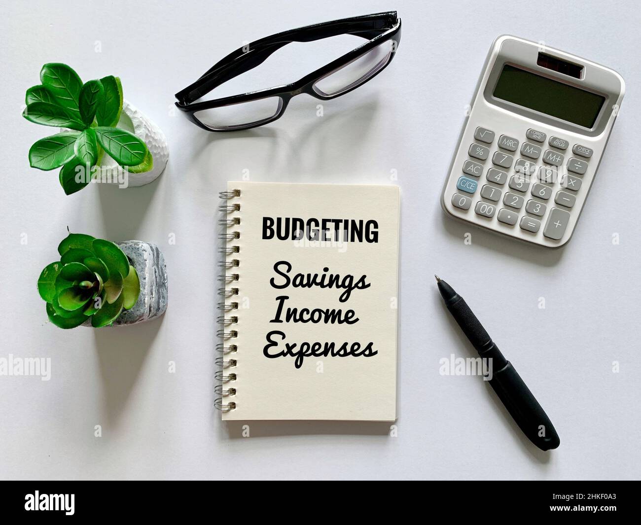 Budgeting text on notepad with white paper, glasses, calculator and pen ...