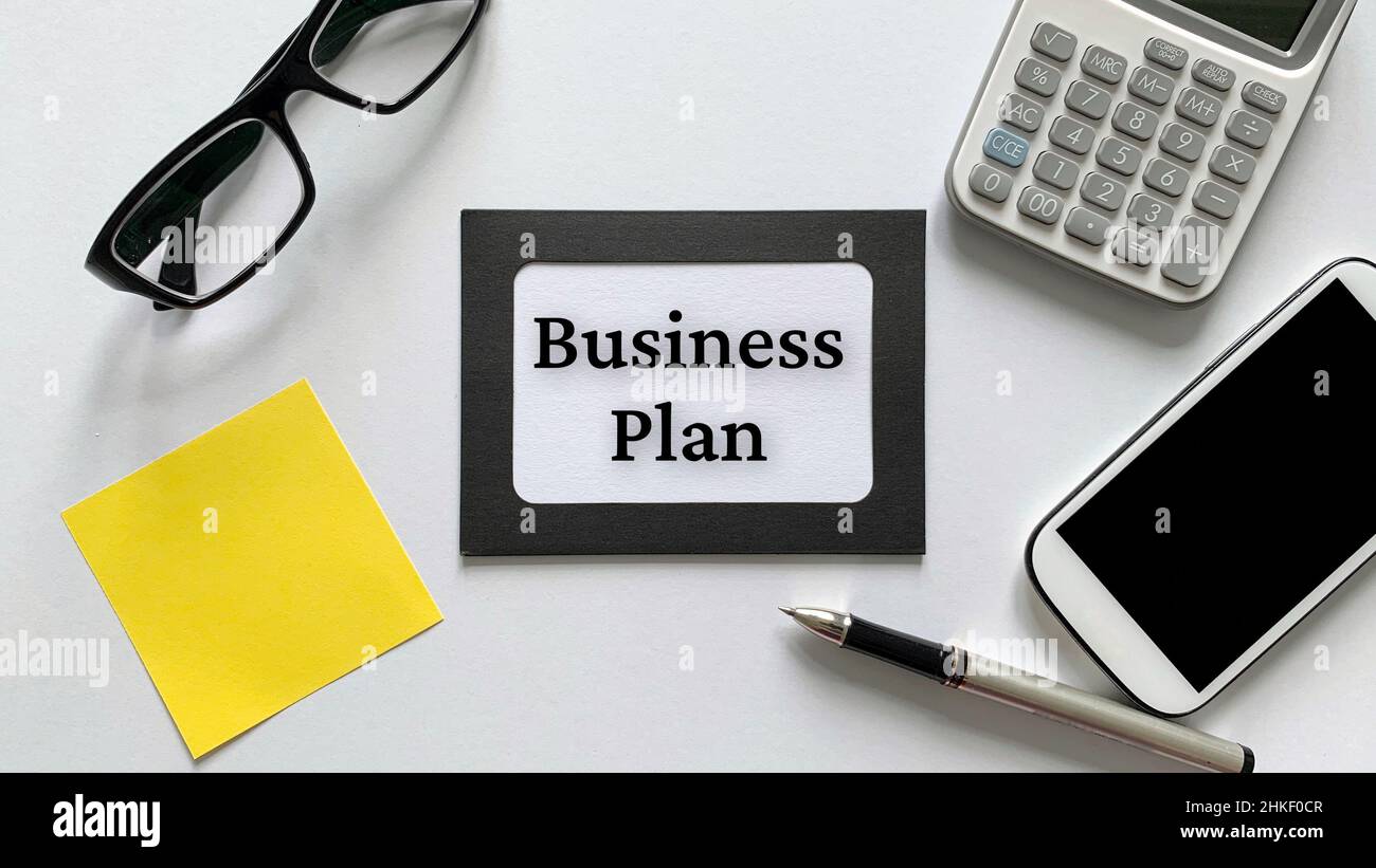 Business plan text on notepad with glasses, calculator, phone and ...