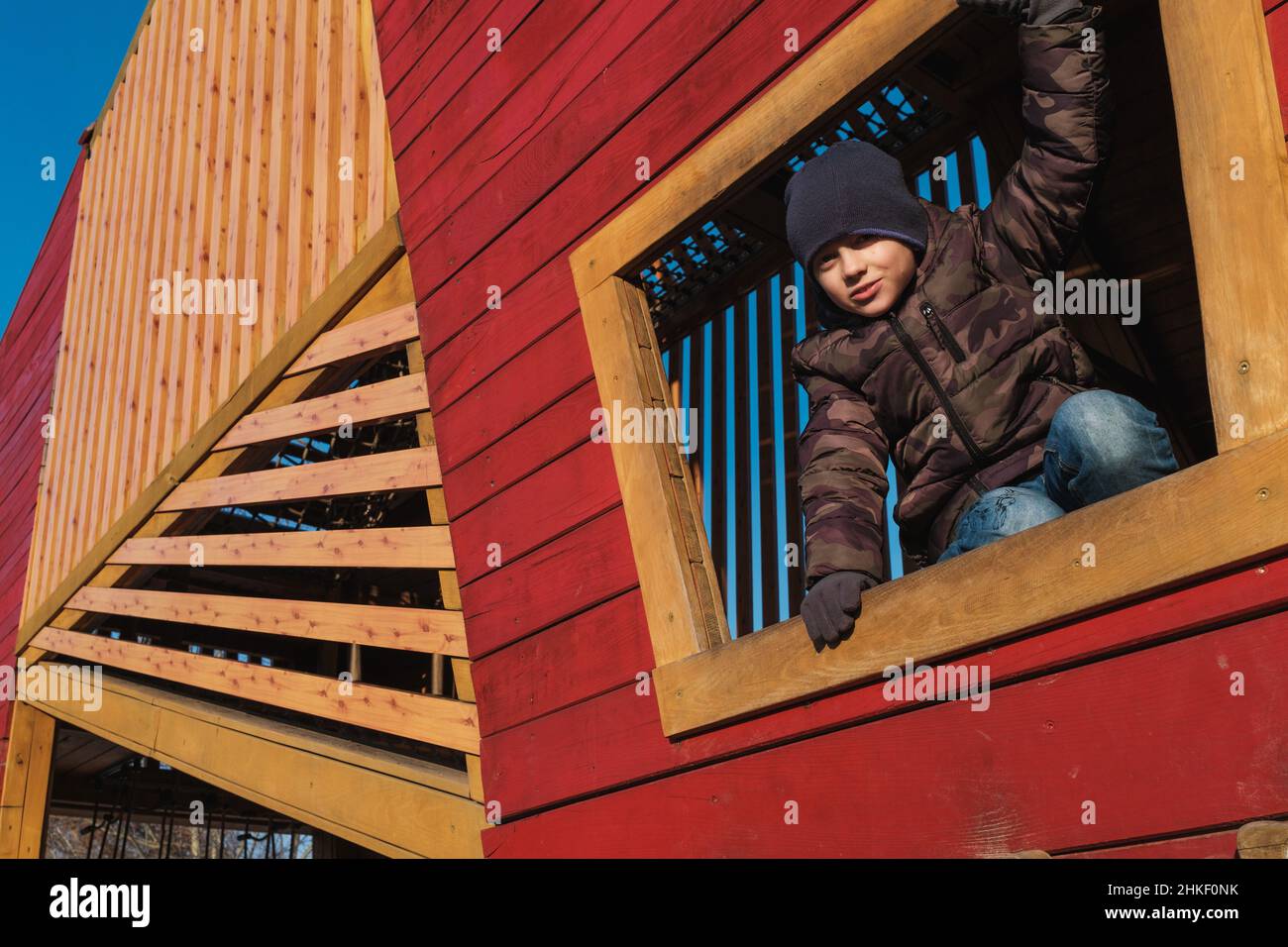 Young boy looks through window in wooden colorful construction Stock ...