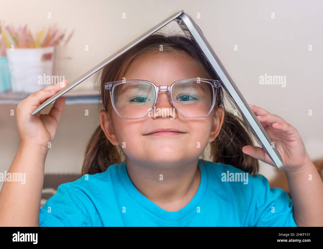 Happy child with glasses holding laptop over head Stock Photo - Alamy