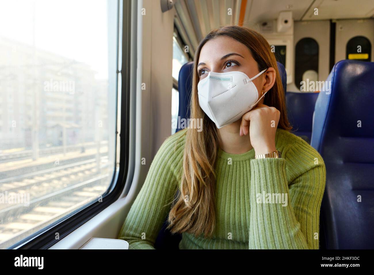 Portrait of relaxed female commuter wearing medical protective mask ...