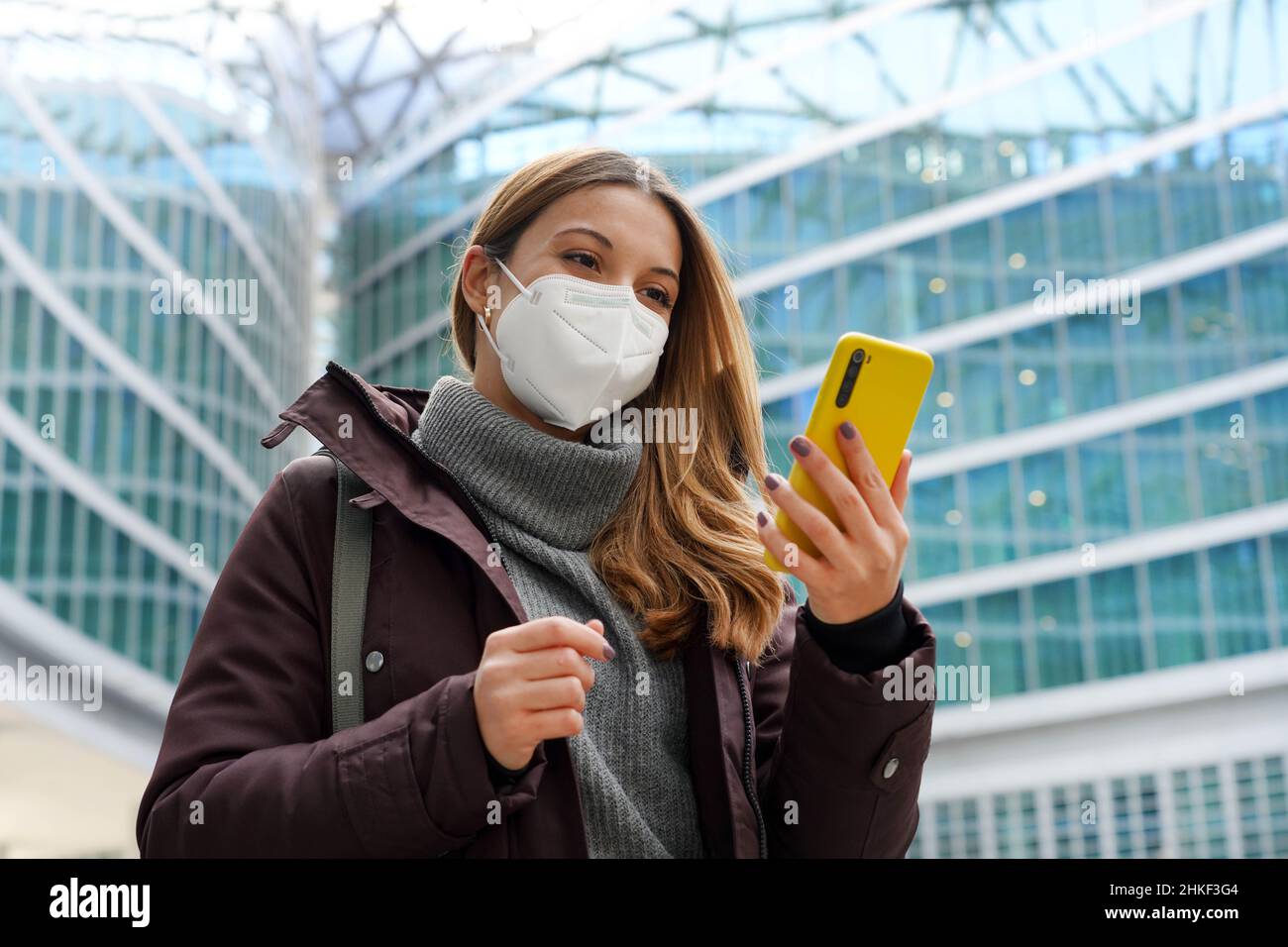 Business woman covering face with protective mask holding mobile phone ...