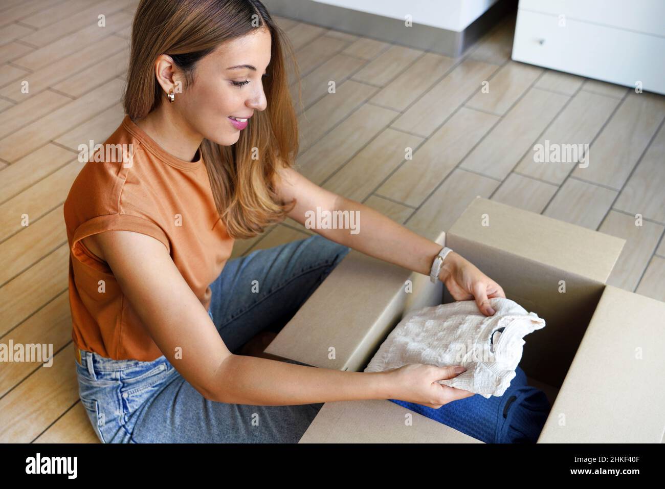 Second hand clothes. Beautiful young woman preparing donation box with ...