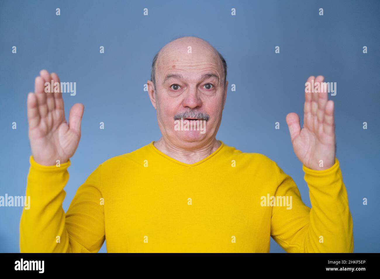 Senior man gesturing with hands showing big and large size sign ...