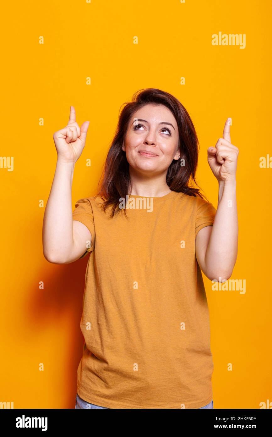 Portrait of joyful adult pointing index fingers up and smiling ...