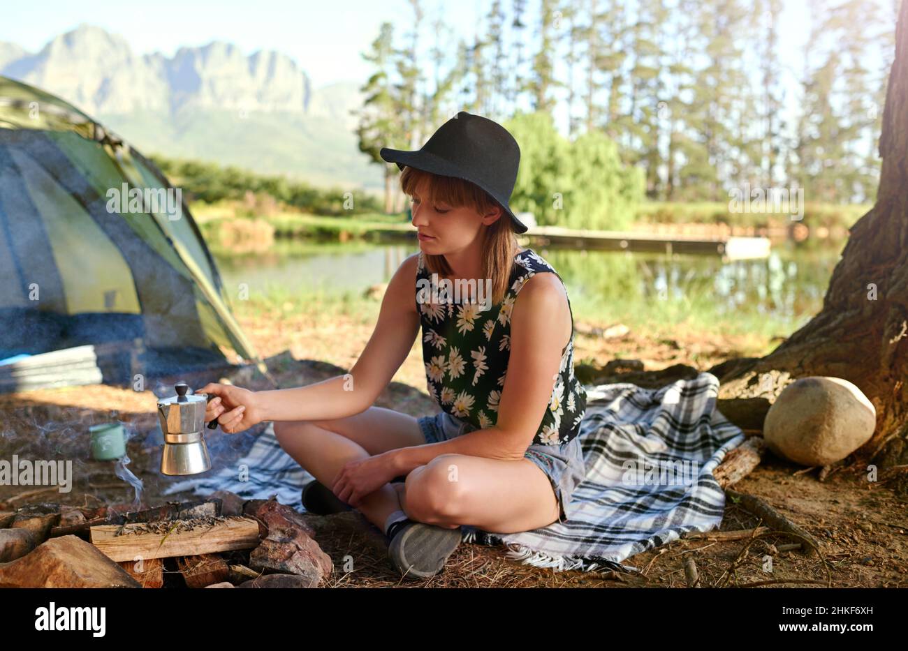 Morning coffee on the brew. Shot of a young woman making coffee over an ...