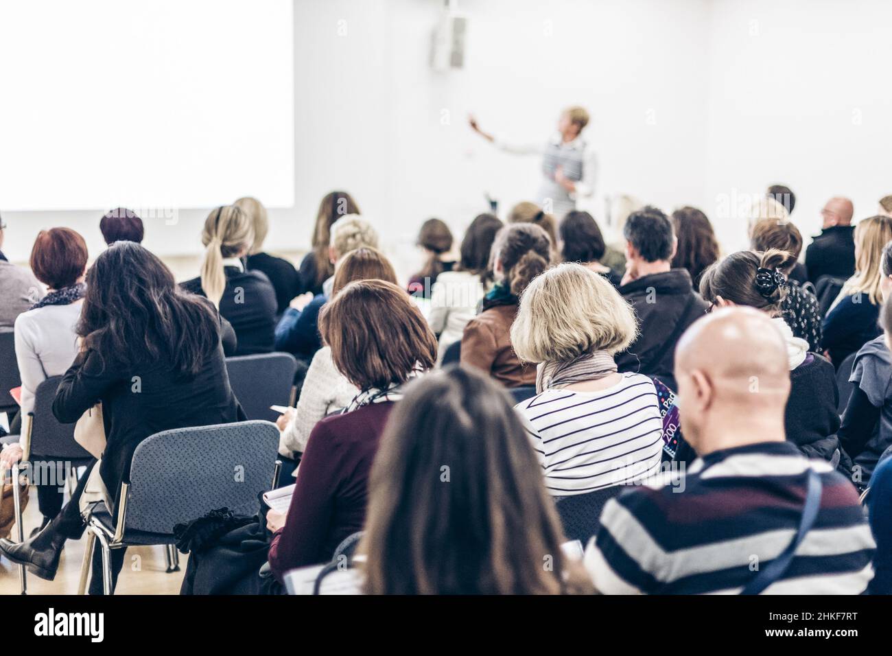 Female speaker giving a talk at business meeting. Audience in ...