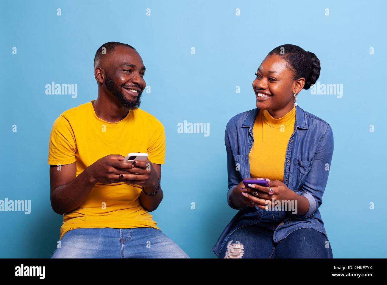 Boyfriend and girlfriend holding mobile phones and smiling at each ...