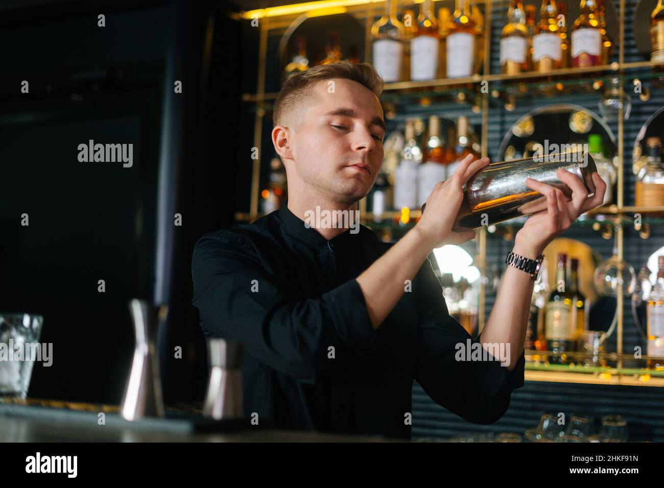 Focused professional barman mixing ingredients of alcoholic cocktail by ...