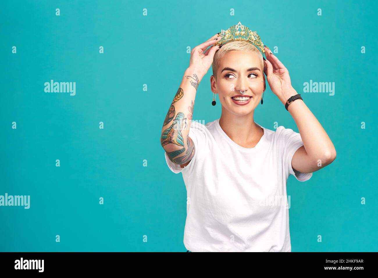 If the crown fits. Studio shot of a young woman putting a crown her ...