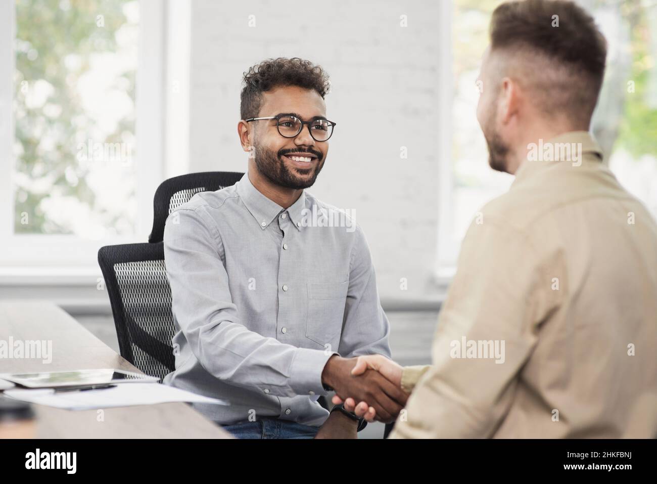 Young men wearing smart casual clothes shaking hands while working ...