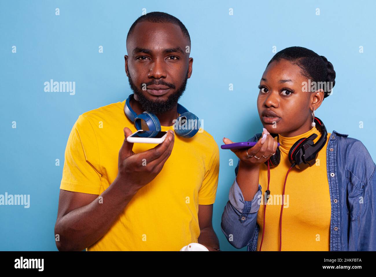 Young couple using speaker on mobile phone to record message, wearing ...