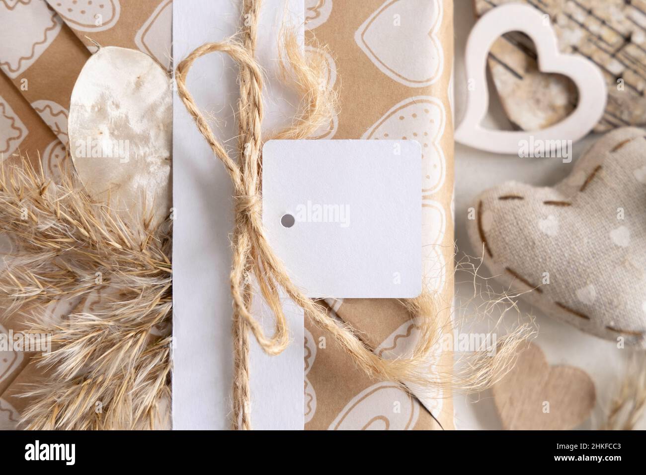 Valentines kraft paper wrapped present with square gift tag, hearts and ...