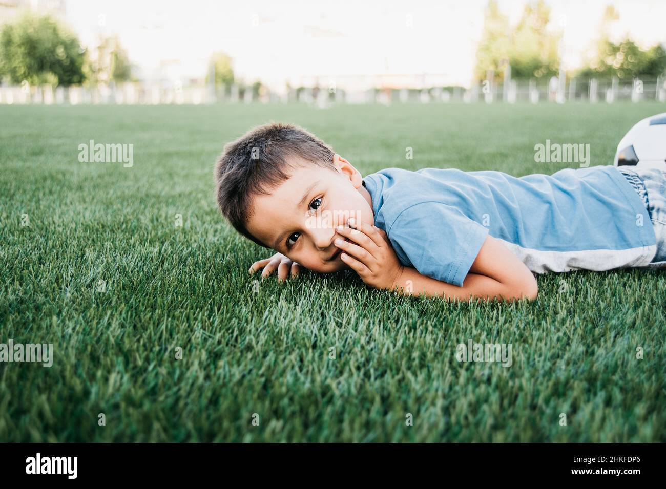 portrait of happy boy lying on football field. sports section. Training ...