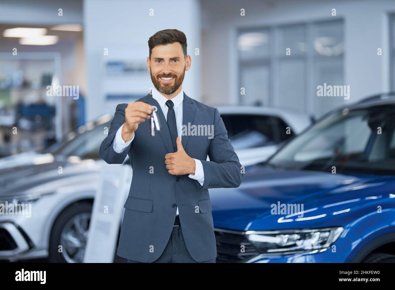 Front view of caucasian businessman showing thumb up and holding keys ...