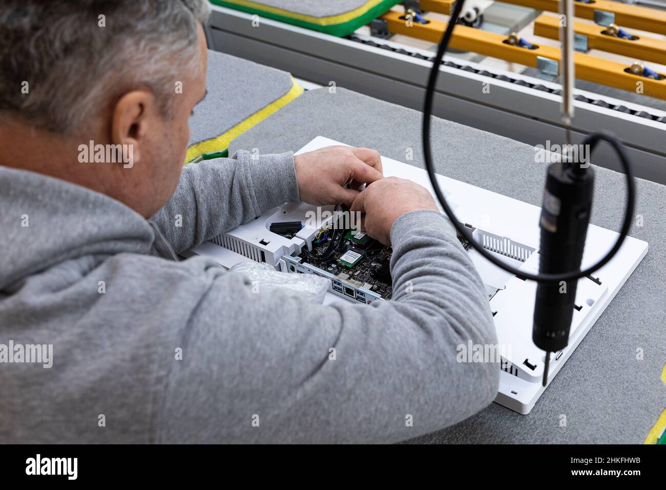 Photo of an adult man in a gray sweater who assembles a computer ...