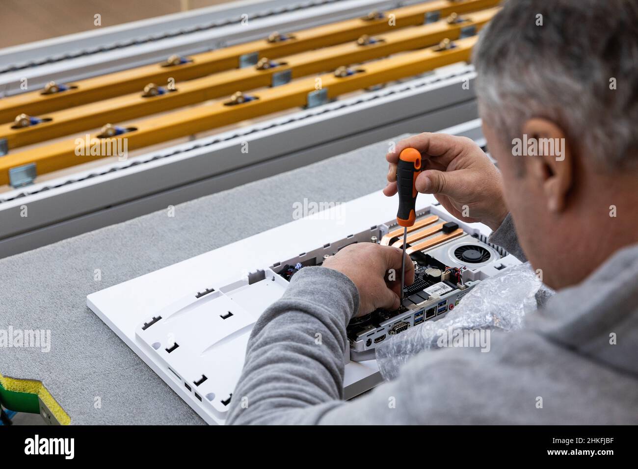 Photo of an adult man in a gray sweater who assembles a computer ...