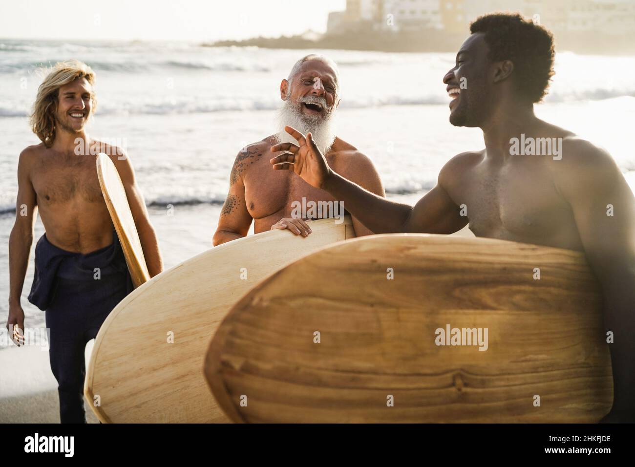 Multi generational surfer friends having fun on the beach after surf ...